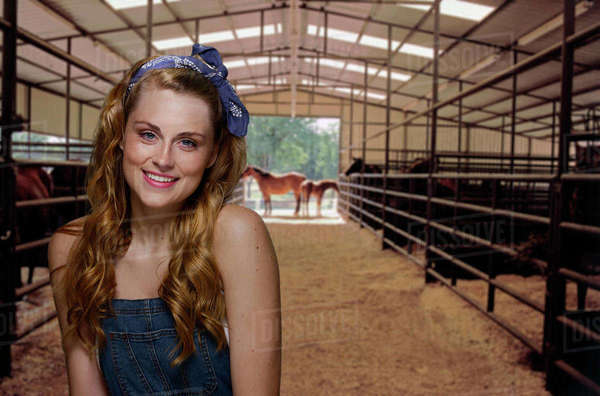 Smiling woman standing in barn - Royalty-free Stock Photo | Dissolve