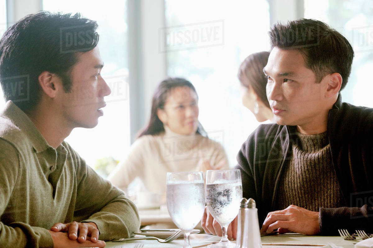 Asian men talking in restaurant - Royalty-free Stock Photo | Dissolve