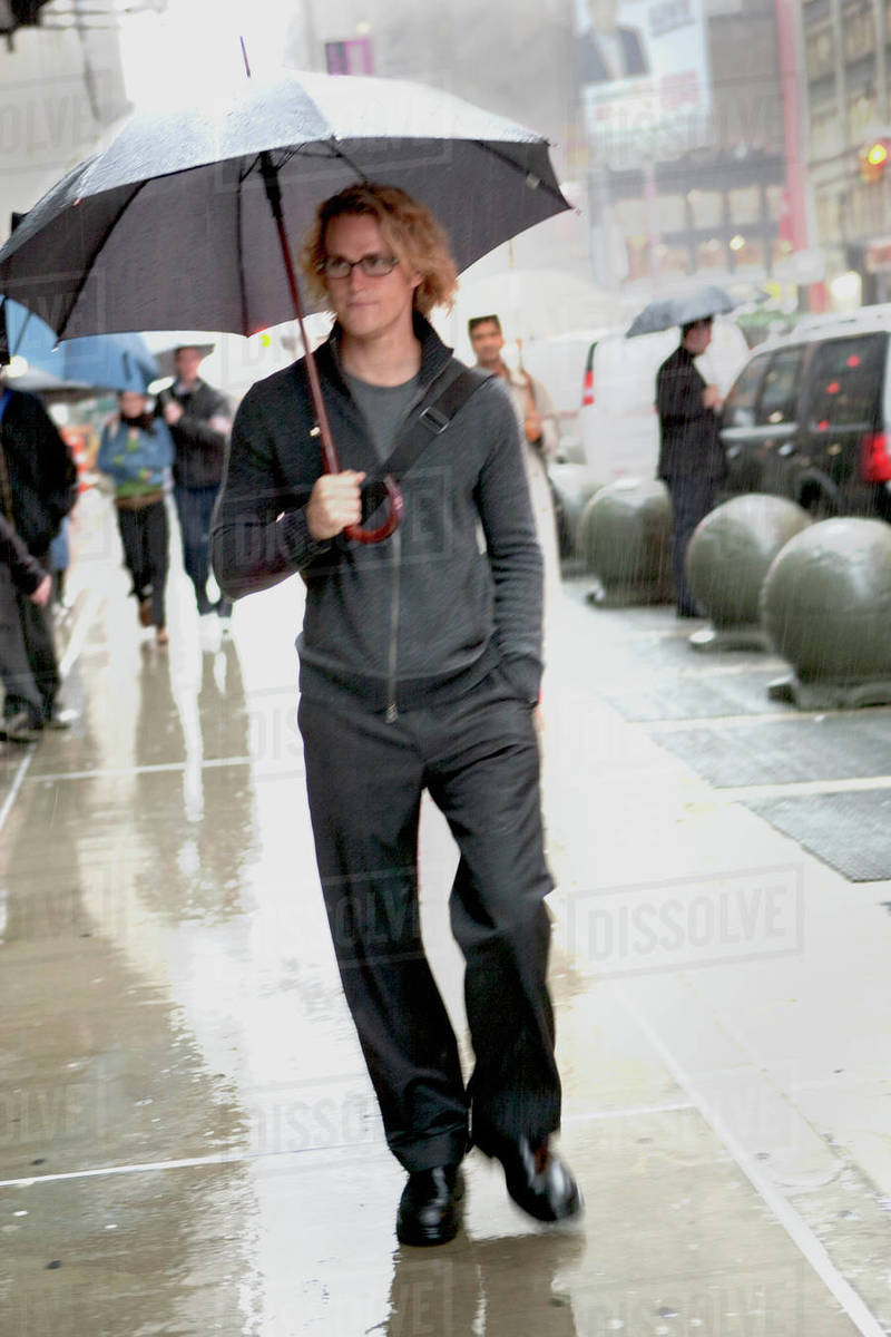 Caucasian man walking in rain with umbrella - Royalty-free Stock Photo ...