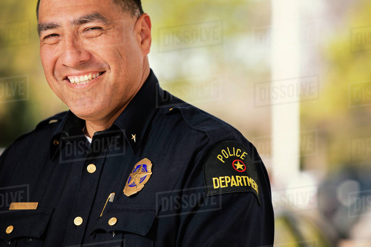 Portrait of Police officer standing outside with arms crossed looking ...