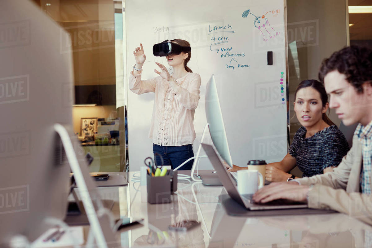 Co-Workers working on computer in office while woman is using Virtual ...