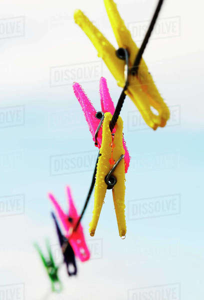 Different coloured pegs clipped on washing line - Stock Photo - Dissolve