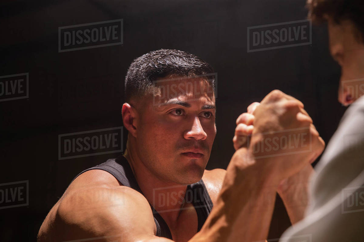 Two men preparing to have miss-matched arm wrestling contest in dingy ...