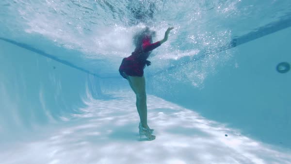 Underwater view of Black woman wearing dress falling into swimming pool ...