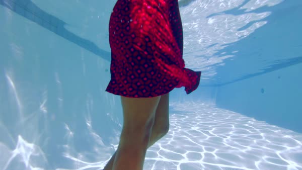Underwater view of Black woman wearing heels dancing in swimming pool ...