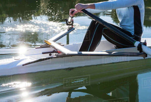 Close up of young woman in single scull kayak rowing on river - Stock ...