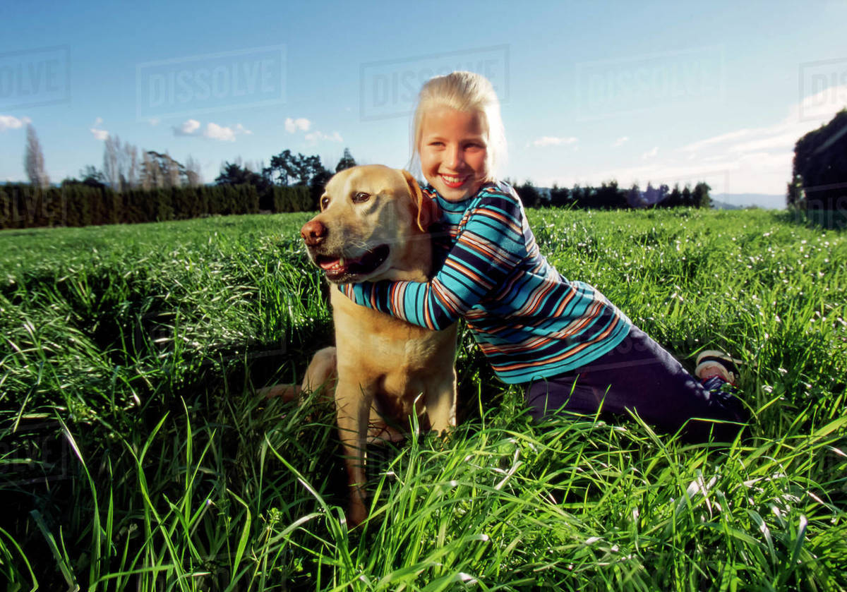 Girl and golden labrador dog sitting in green field - Royalty-free ...