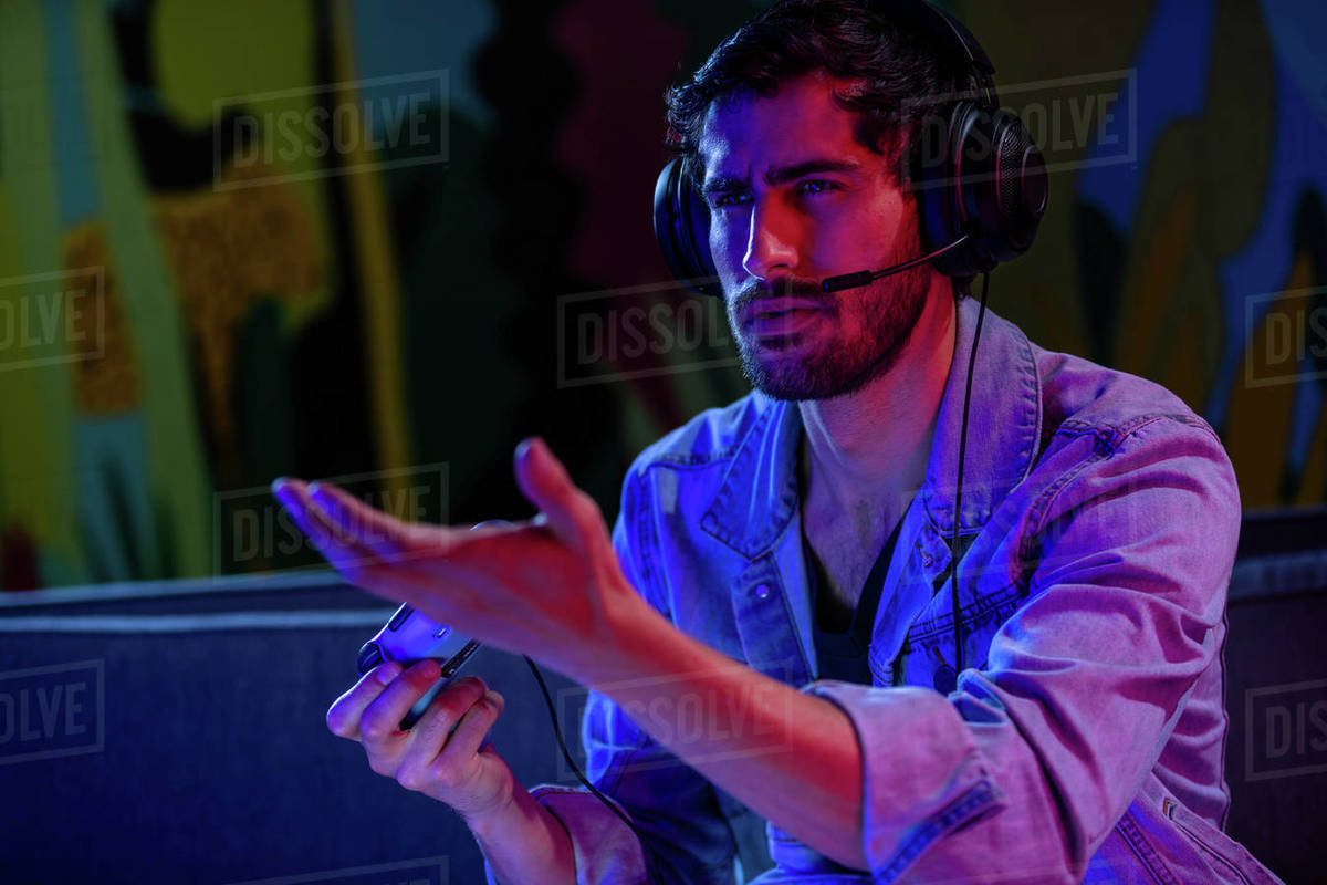 Angry young man making a gesture at TV while playing video game ...