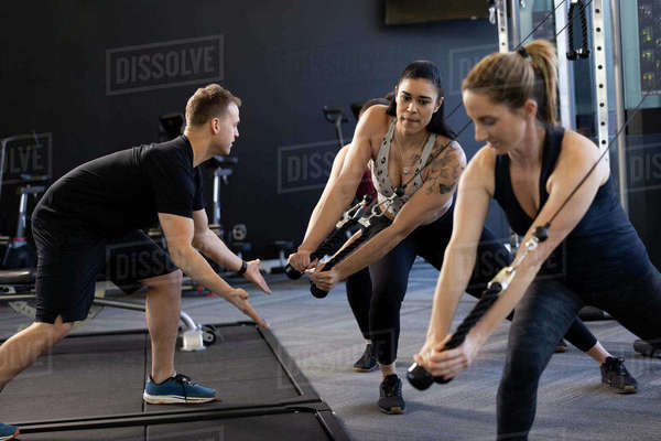 Personal trainer encouraging three women while they work out on rope ...