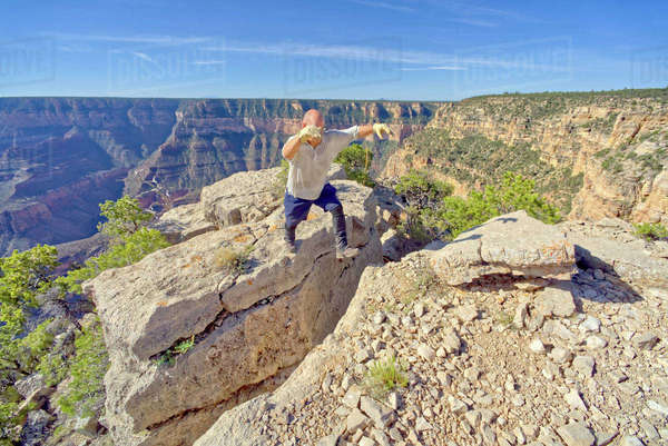 A man jumping across a cliff crevice east of Shoshone Point at Grand ...