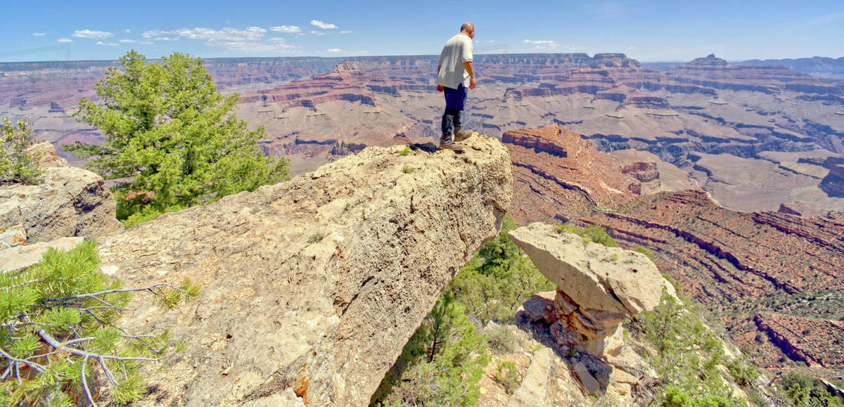 A man looking over the edge of a cliff overhang west of Shoshone Point ...