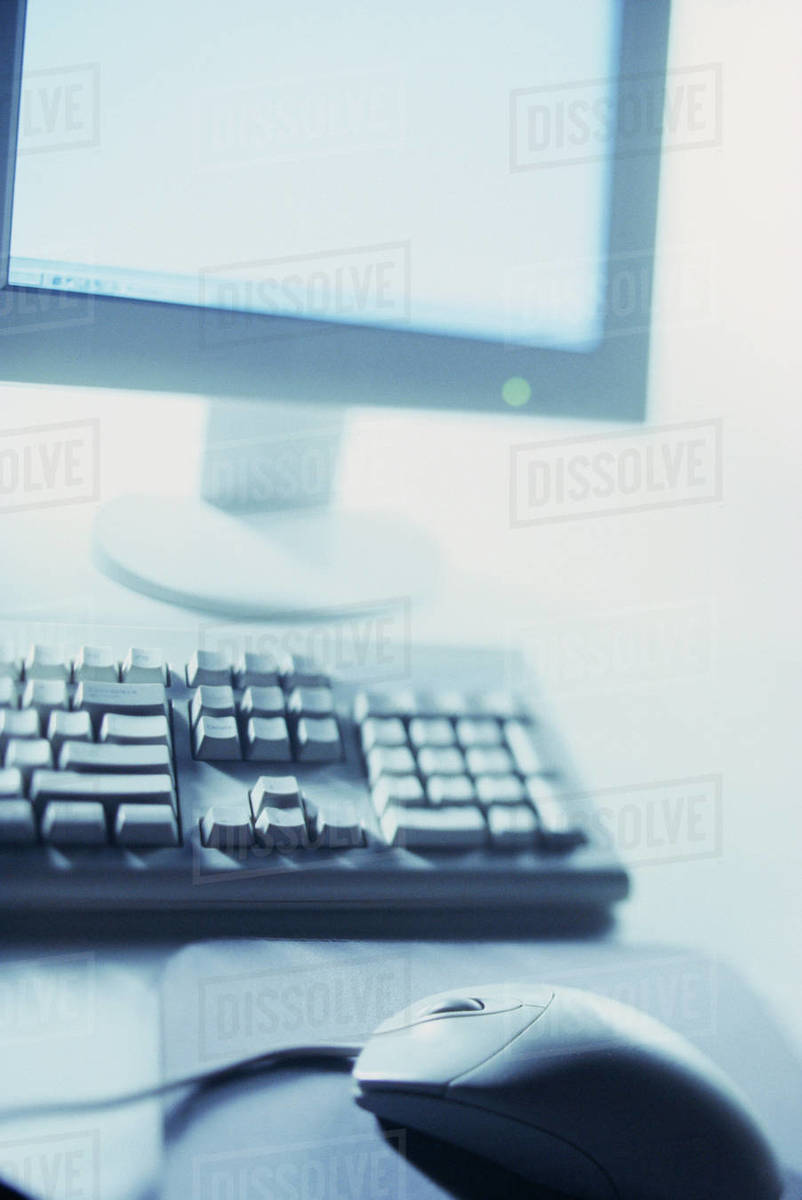 Close-up of a computer keyboard in front of a computer monitor ...