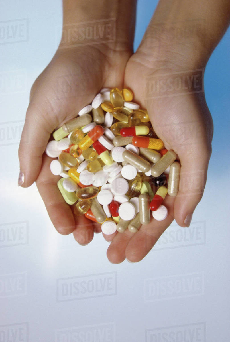 Person's hands holding an assortment of tablets and capsules - Royalty ...