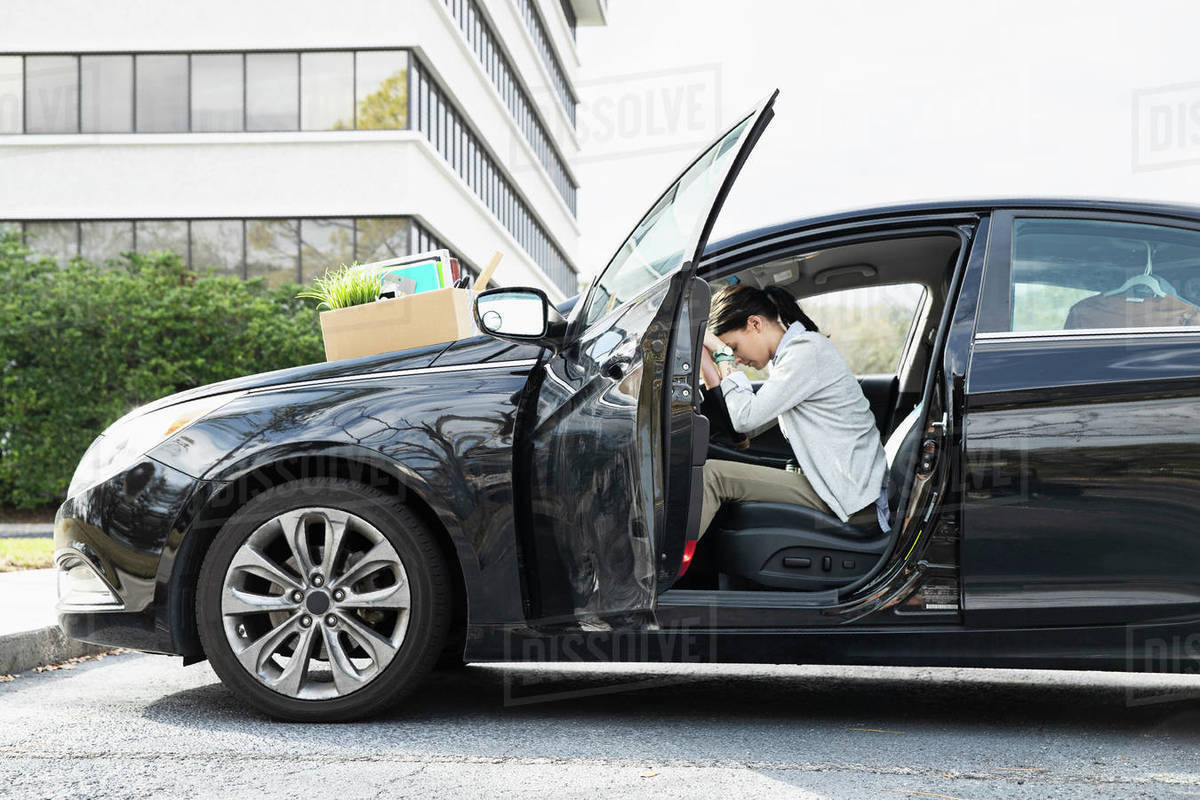 A woman leaning over her steering wheel outside of her office - Royalty ...