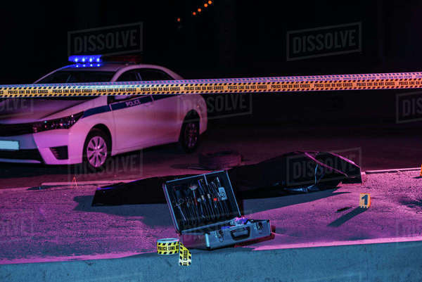 toned picture of crime scene with police car, case with investigation ...