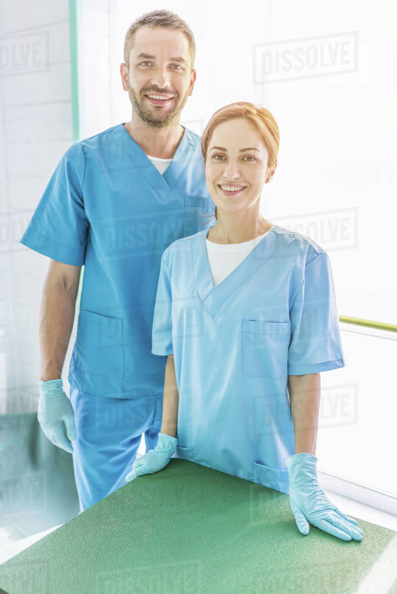 smiling two veterinarians standing in uniform and looking at camera at ...