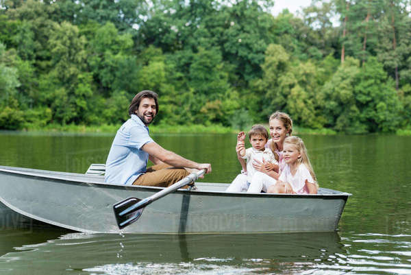 Side view of young family riding boat on lake at park - Royalty-free ...