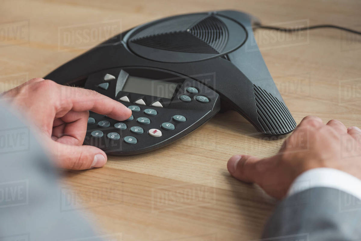 Cropped shot of businessman pushing button of conference phone on ...
