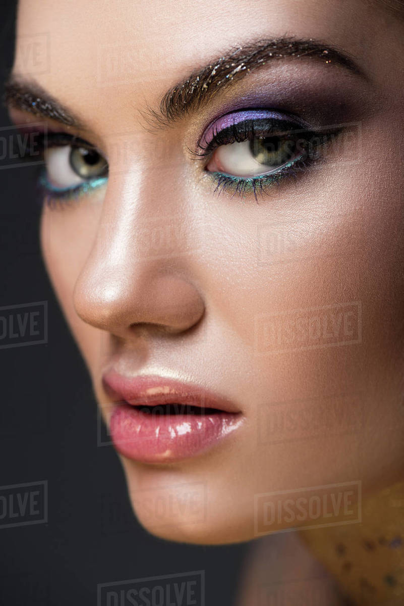 Close up of young model with glitter makeup on face, isolated on grey ...