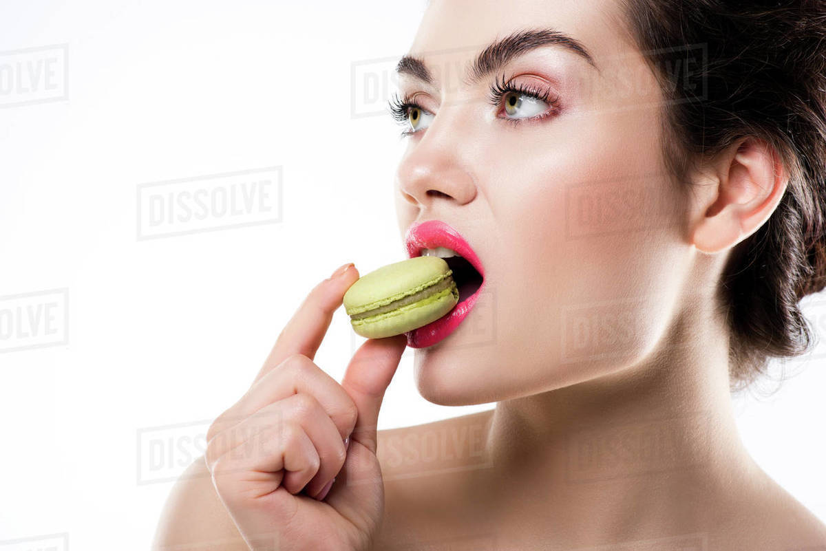 Attractive woman eating green sweet macaron, isolated on white ...