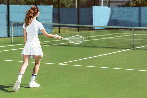 back view of woman in white tennis uniform playing tennis on court ...
