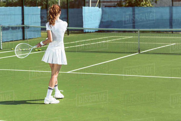 back view of woman in white tennis uniform playing tennis on court ...