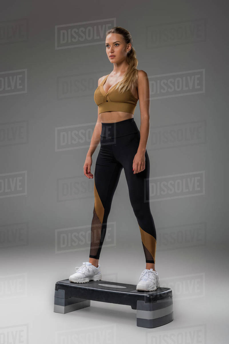 attractive young woman doing step aerobics on grey - Royalty-free Stock ...