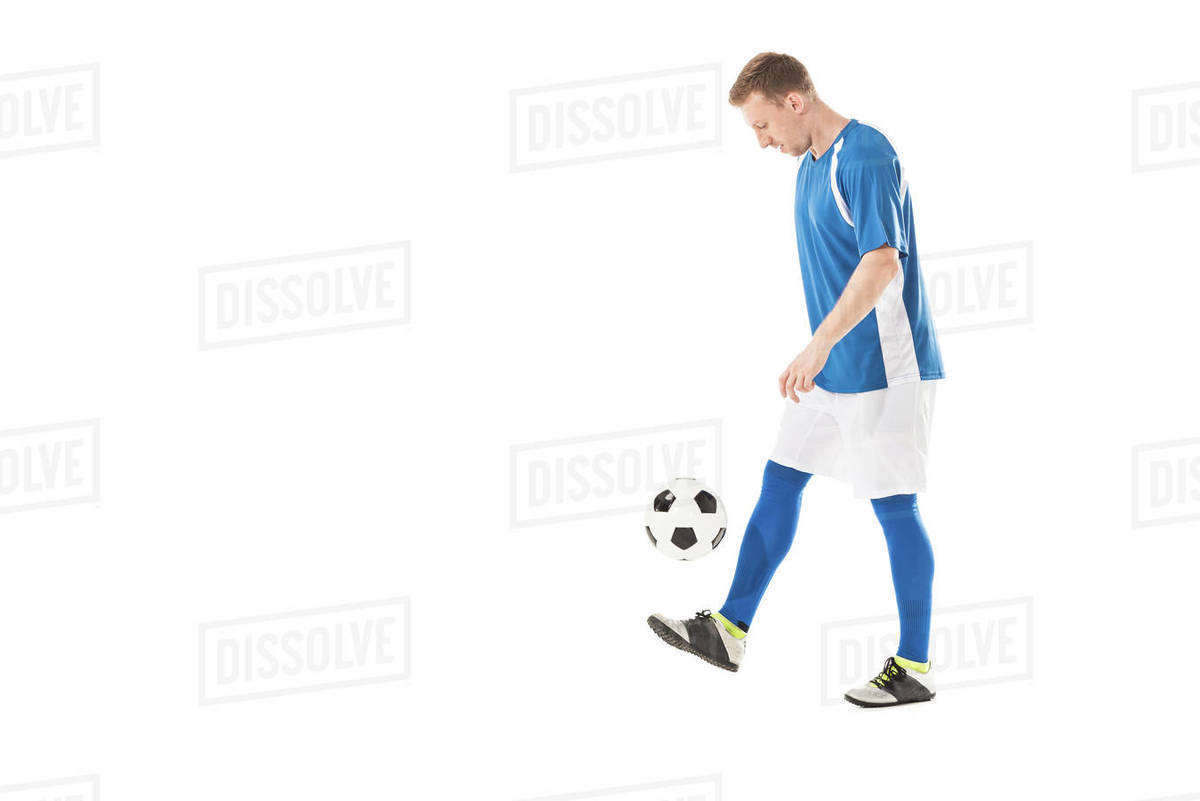 side view of young soccer player kicking ball and looking down isolated ...