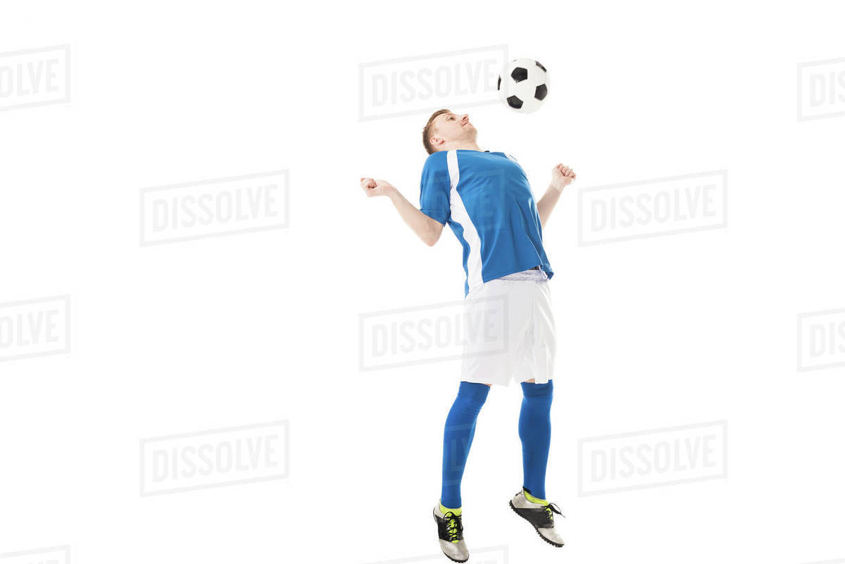 full length view of young soccer player hitting ball with chest ...