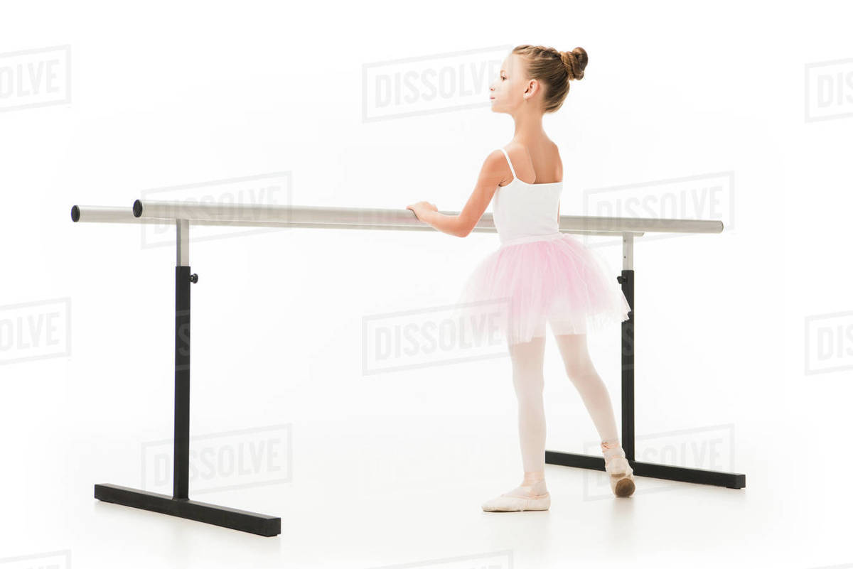 Rear view of beautiful little ballerina in tutu exercising at ballet ...