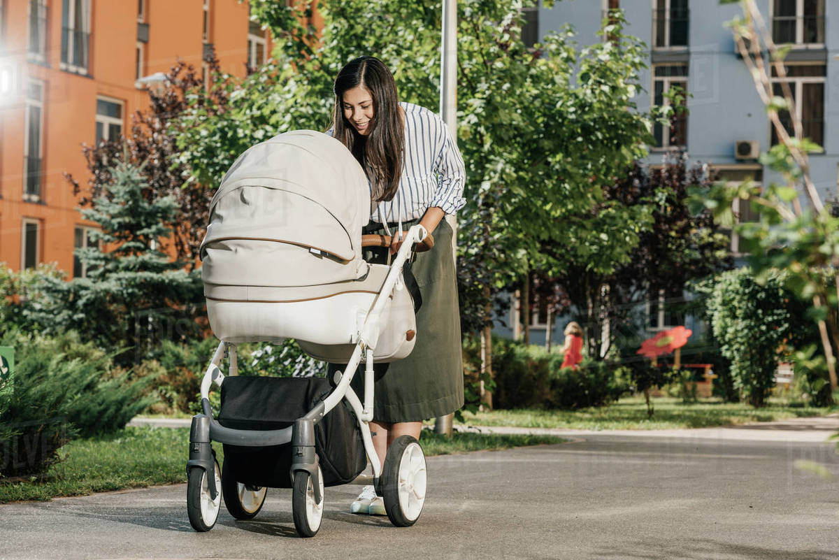 Beautiful mother looking in baby stroller on street - Royalty-free ...