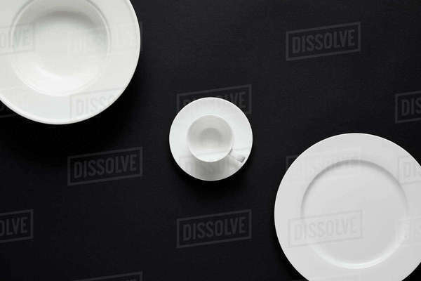 Top view of arranged different plates and cup on black table - Stock ...