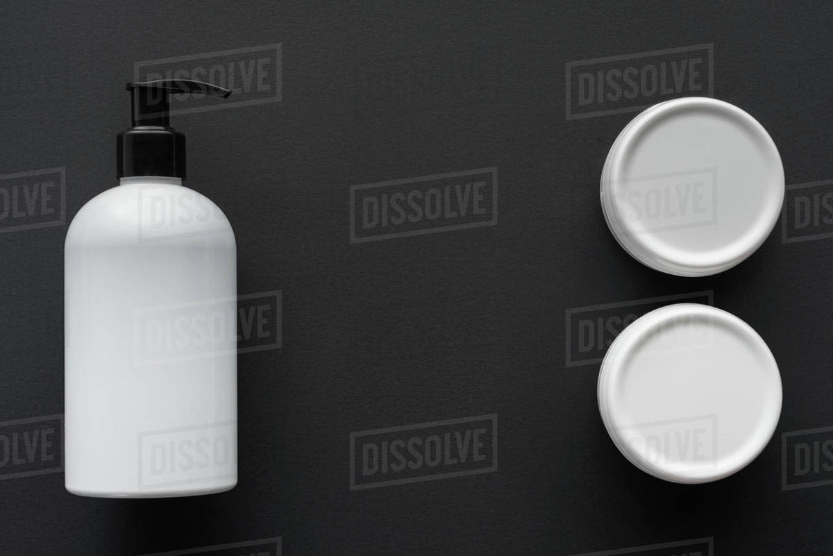 Top view of bottles of lotion and cream isolated on black, beauty ...