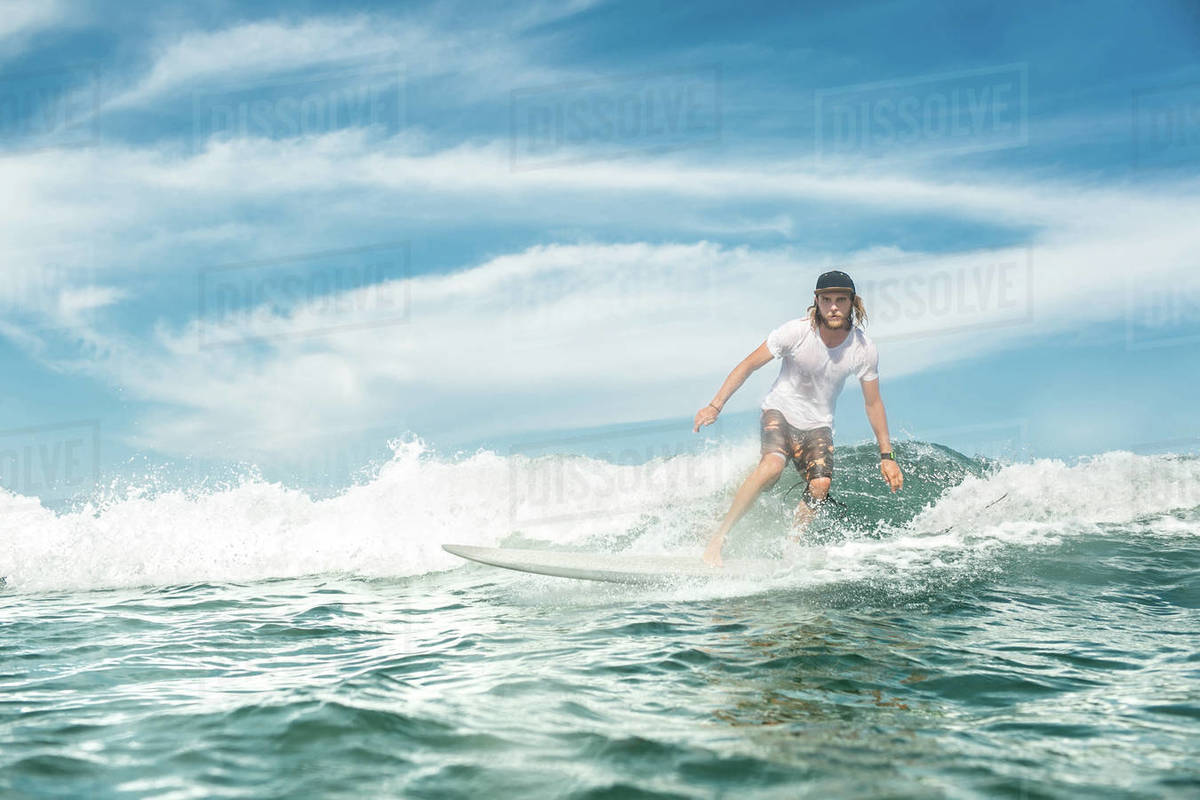 Handsome male sportsman surfing on waves in ocean at Nusa Dua Beach ...