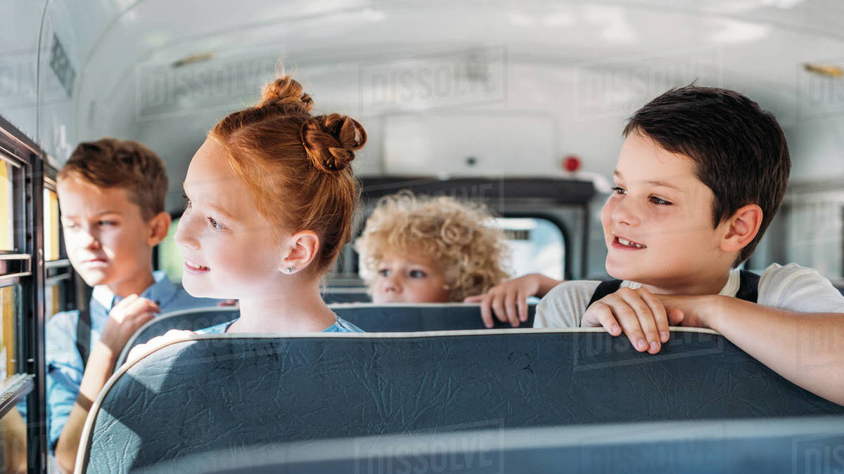 group of schoolchildren riding on school bus and looking through window ...