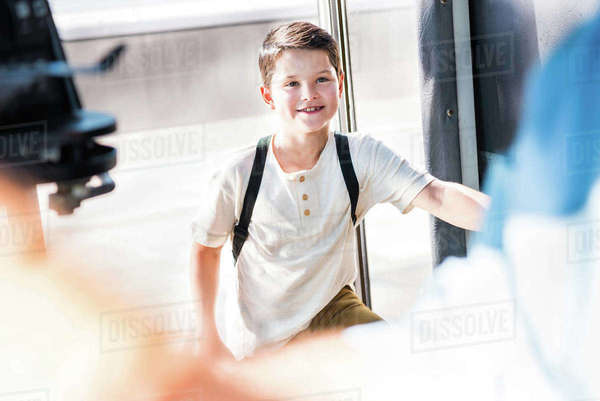 smiling schoolboy entering school bus and looking at driver - Royalty ...