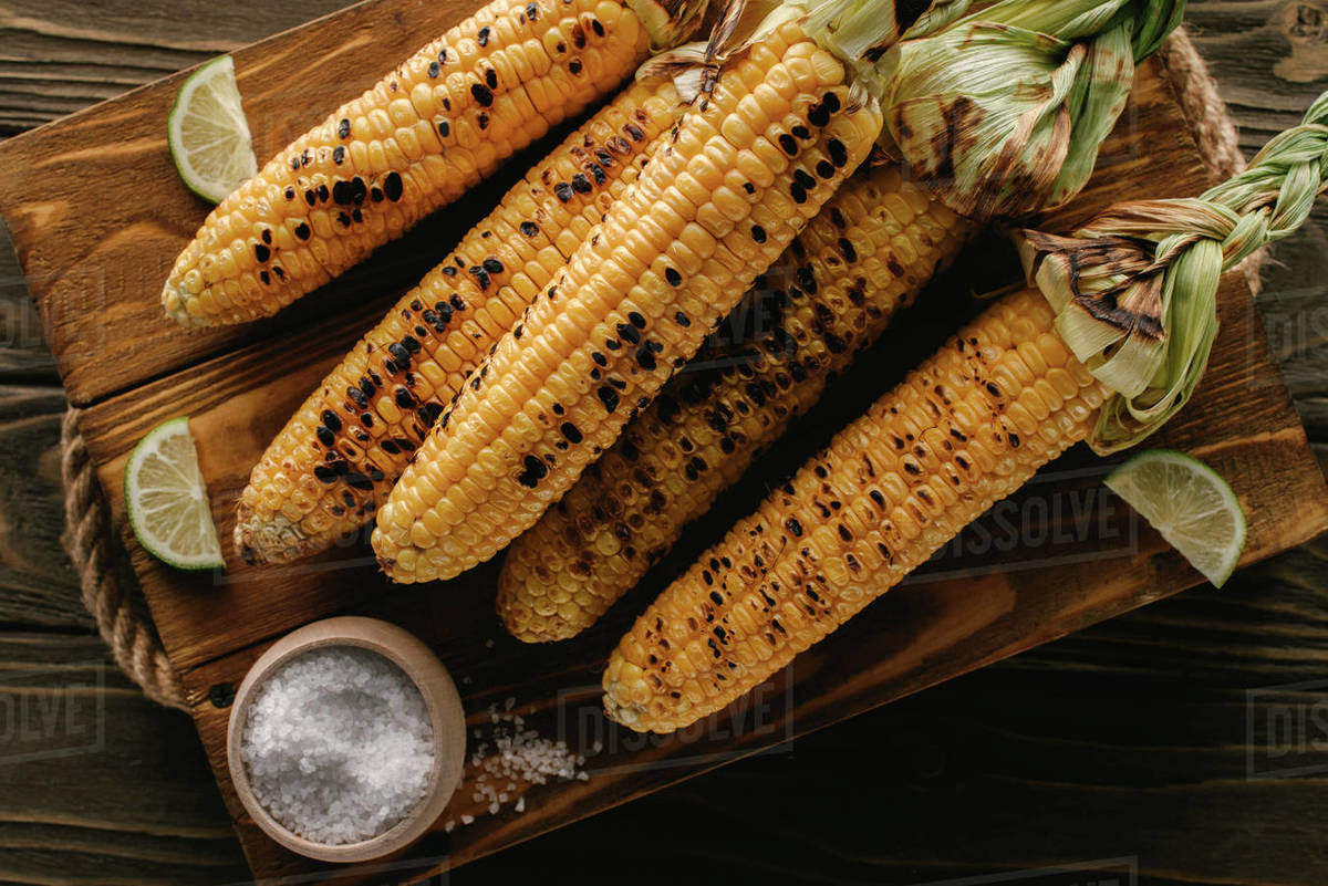 Top view of cutting board with delicious grilled corn, lime slices and ...