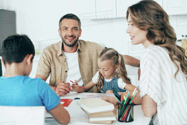 parents helping children with homework at table at home - Royalty-free ...