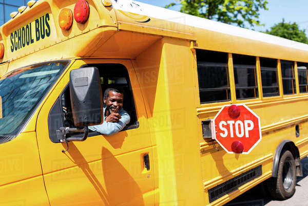 smiling mature african american bus driver looking out window and ...