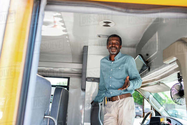 happy mature african american bus driver standing inside bus and ...