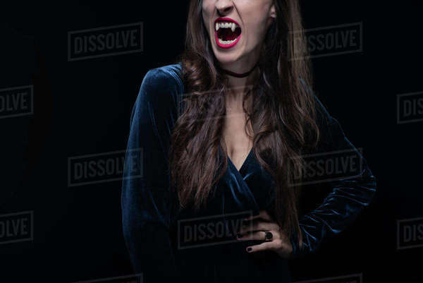 Cropped view of woman showing vampire teeth isolated on black - Stock ...
