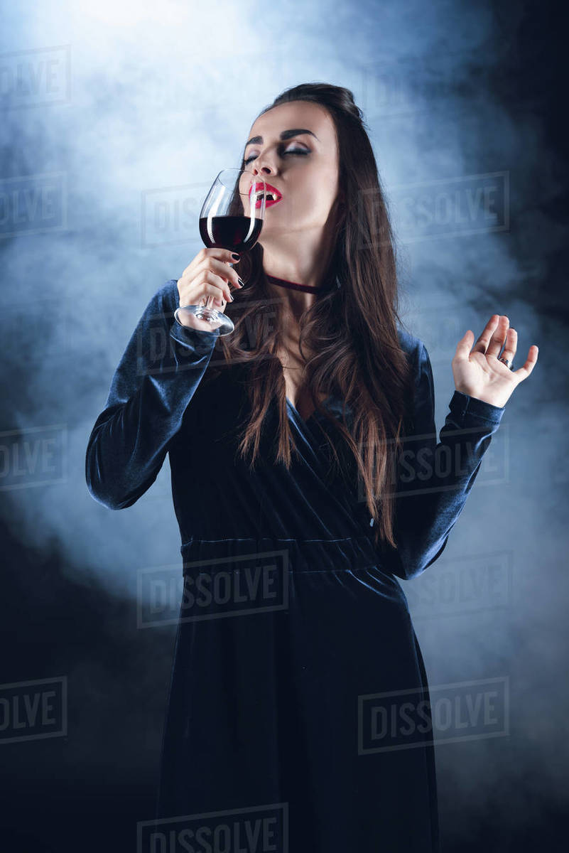 Vampire drinking blood from wineglass on dark background with smoke ...