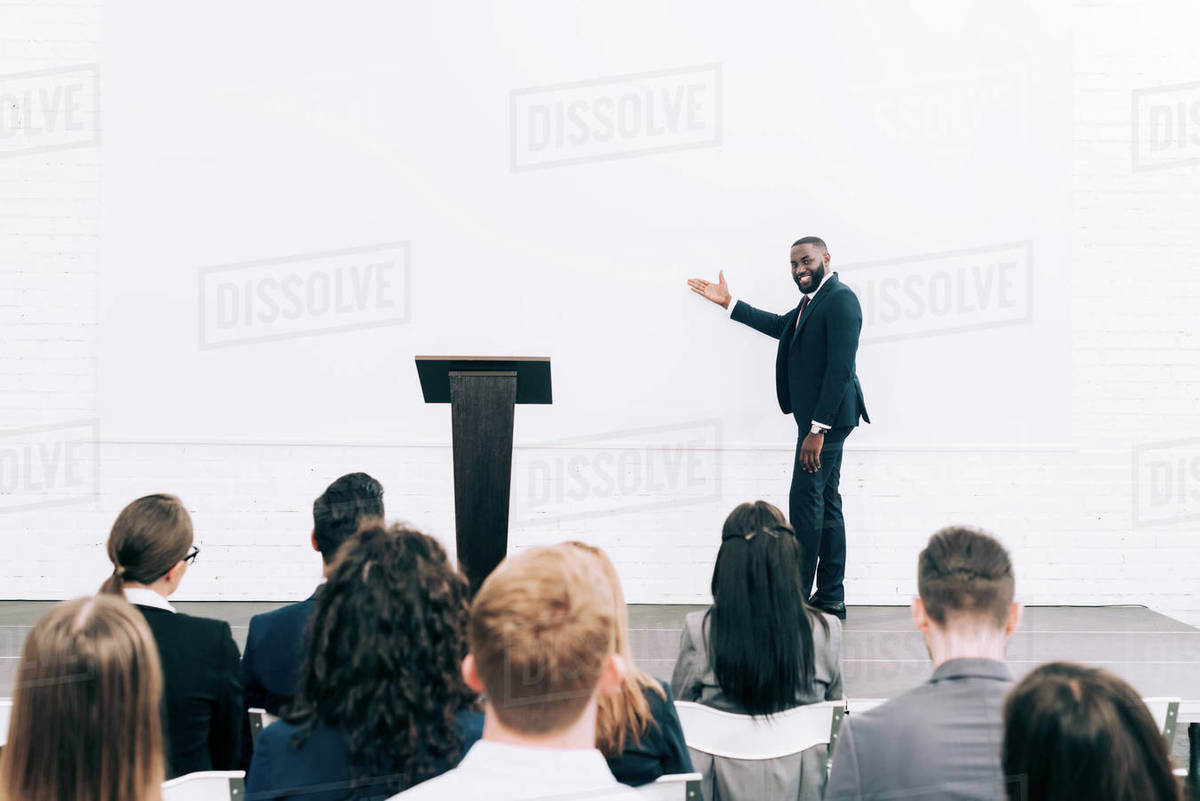 Smiling African American lecturer talking to audience during seminar in ...