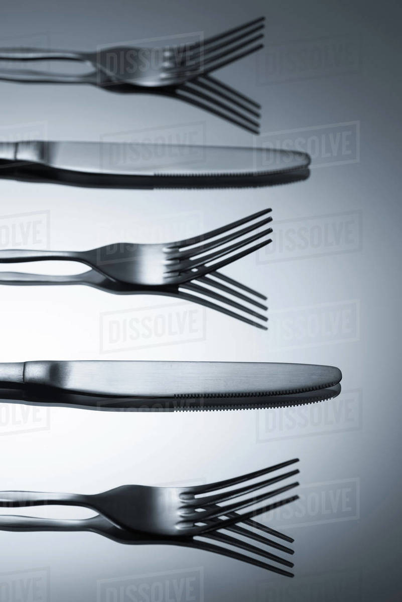 Close-up view of shiny forks and knives reflected on grey - Stock Photo ...