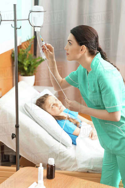 Doctor with drop counter and little patient lying on bed in hospital ...
