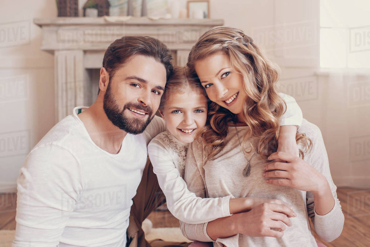 Happy young family with one child hugging and smiling at camera - Stock ...