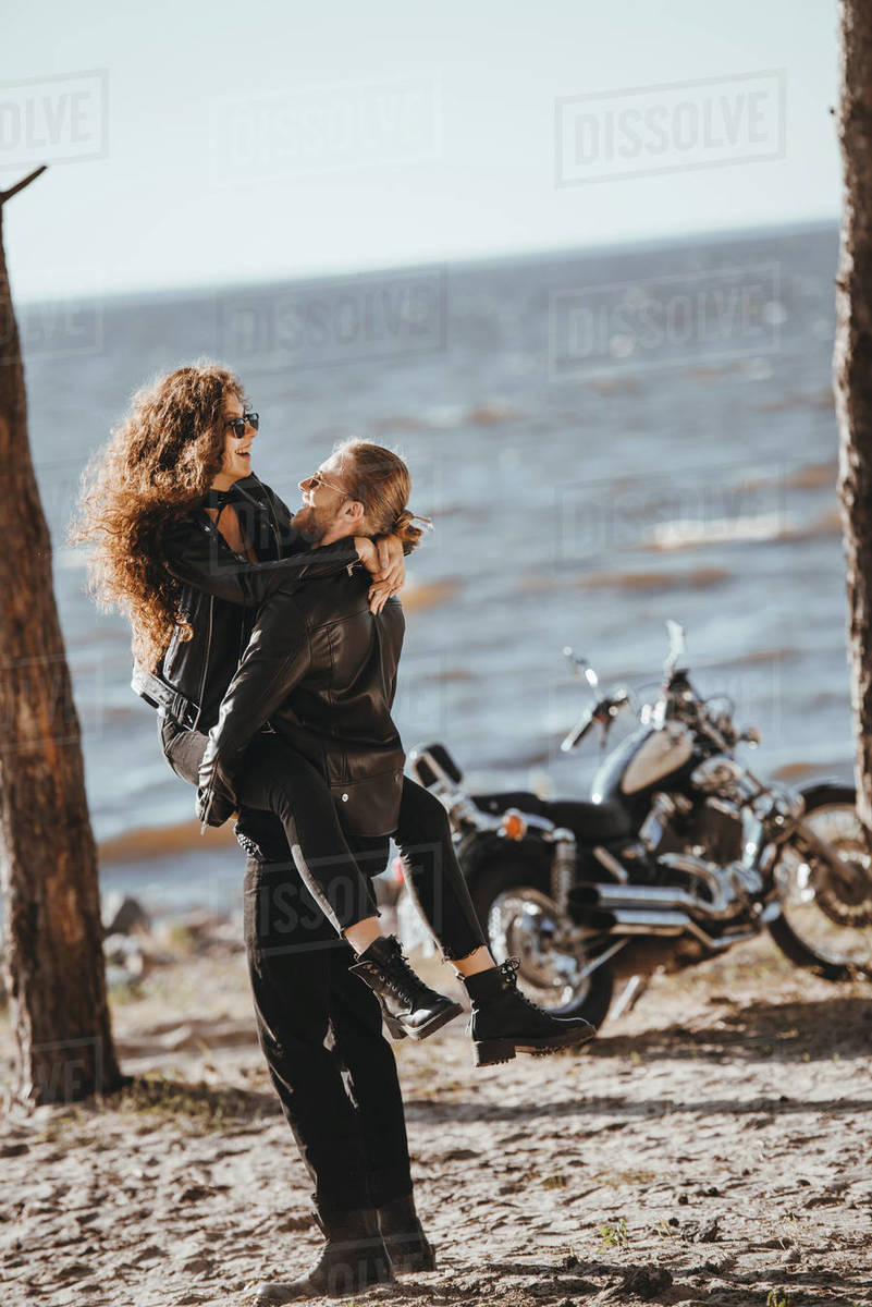 Couple having fun on seashore with chopper motorcycle near - Royalty ...