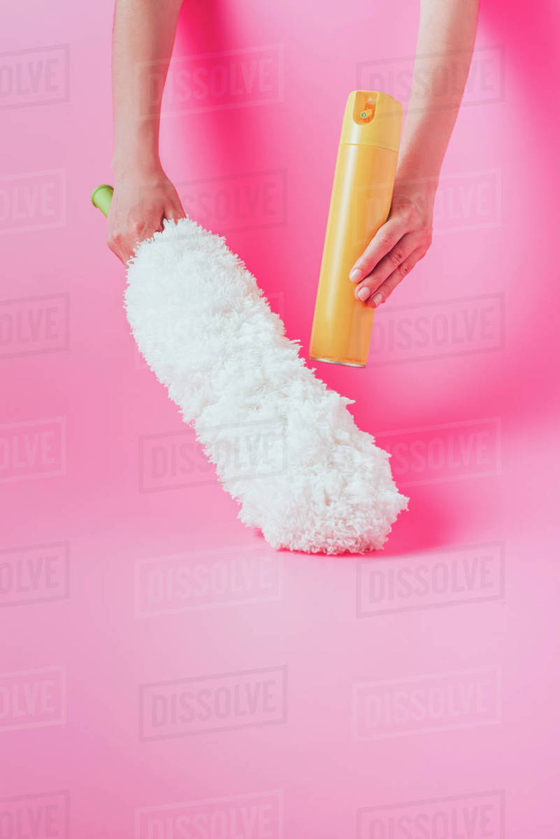 cropped image of female cleaner holding spray can and white duster ...