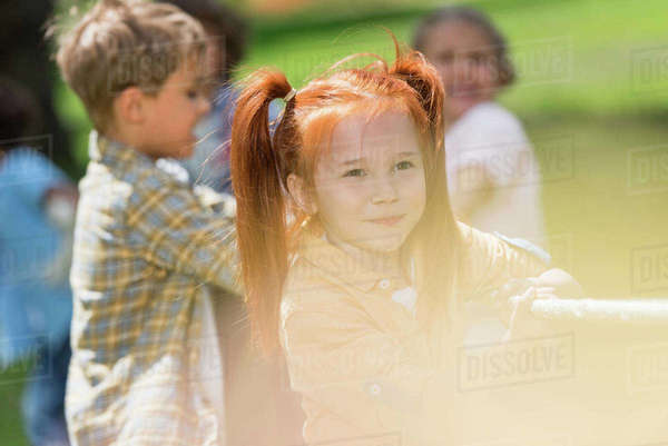 adorable little redhead girl pulling rope with friends in park - Stock ...