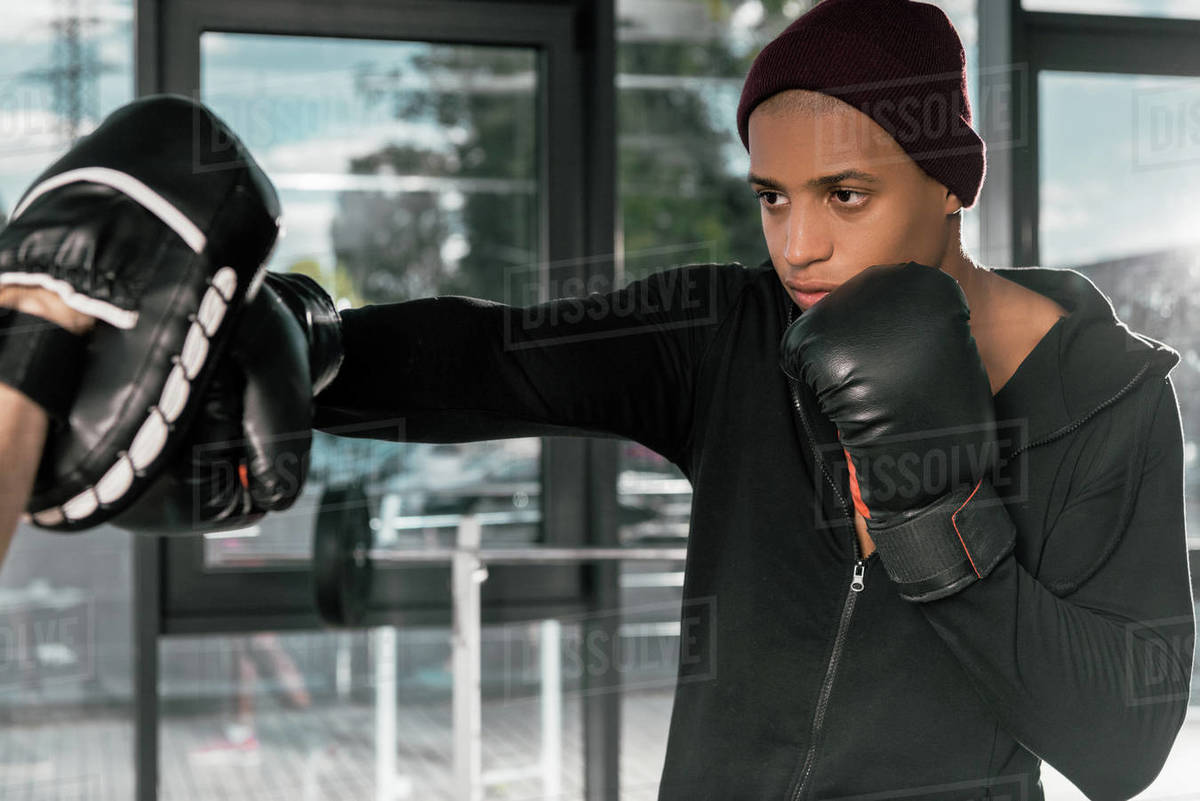 young african american boxer in boxing gloves practicing with trainer ...